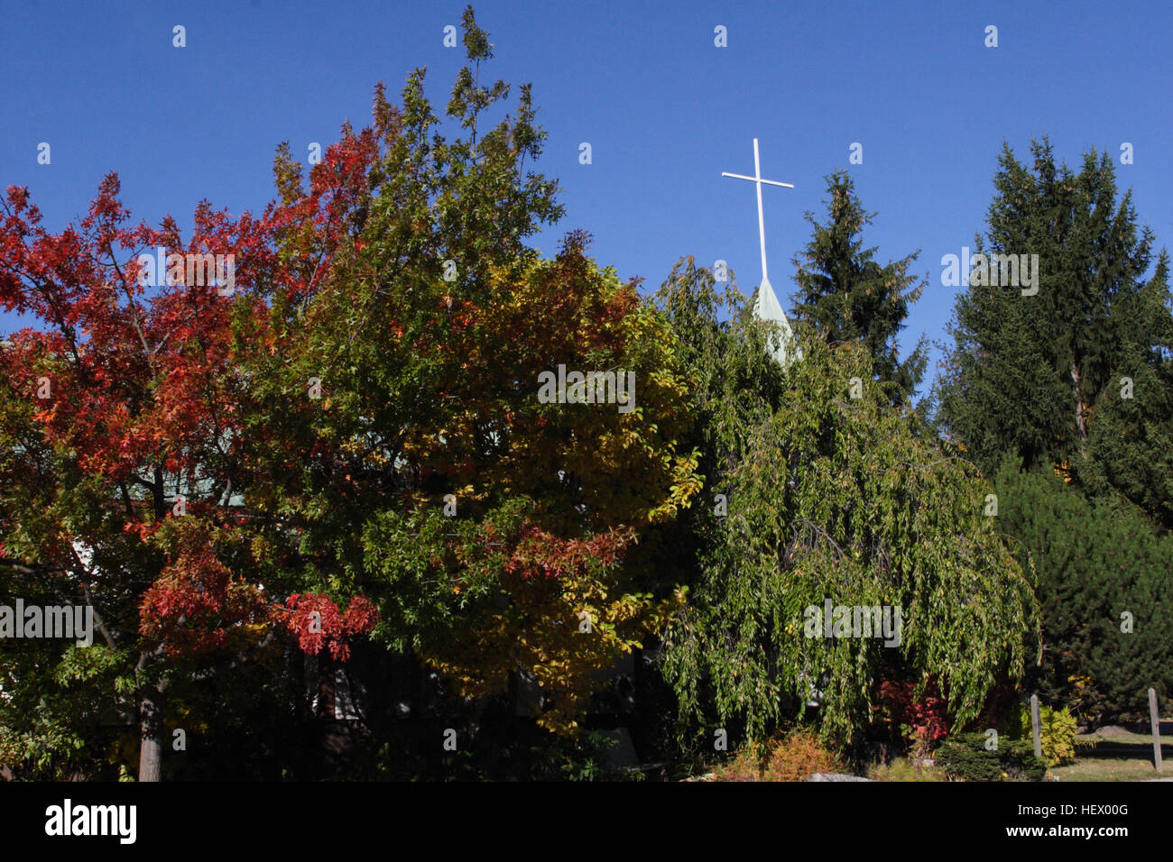 White cross on church rises above fall foliage Stock Photo - Alamy