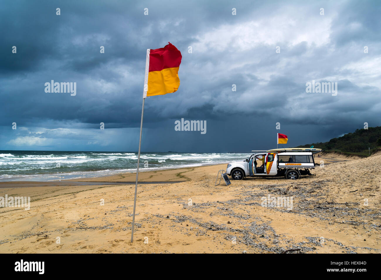 The red and yellow flag and 4wd of a lifeguard patrol on a stormy beach ...