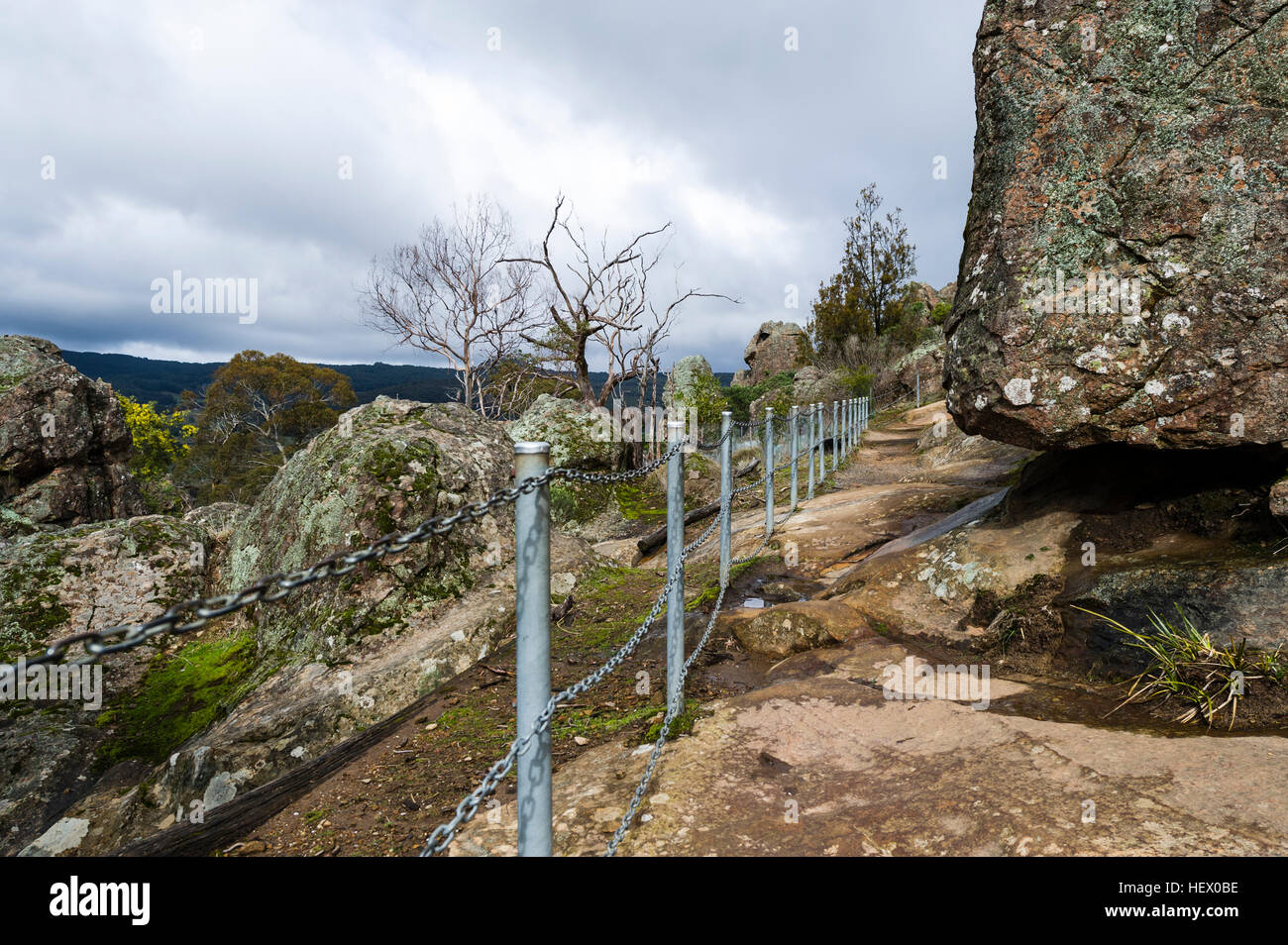 A hiking trail safety rail follows a path around a rock pillar made of ...