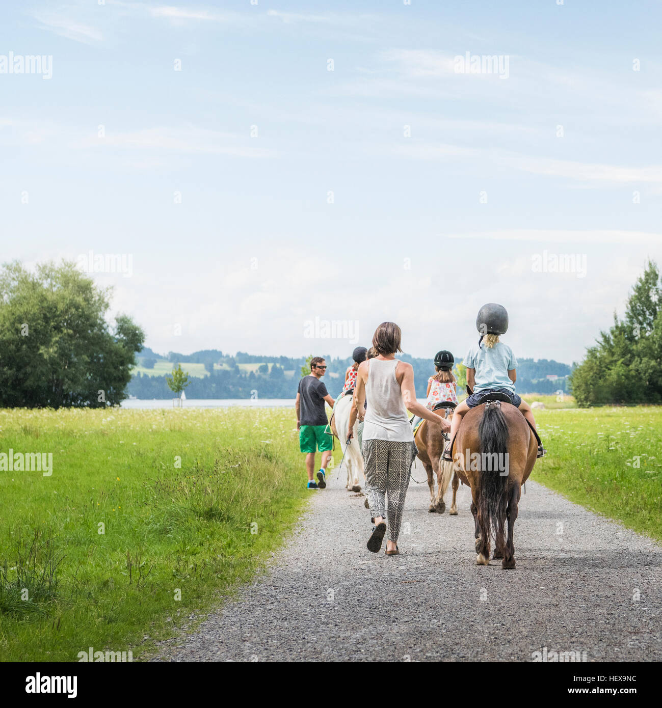Rear view of parents guiding children on horse, Fuessen, Bavaria ...