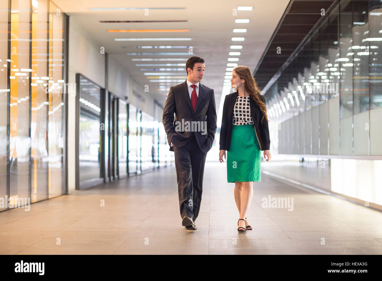Businesspeople walking in corridor talking Stock Photo - Alamy