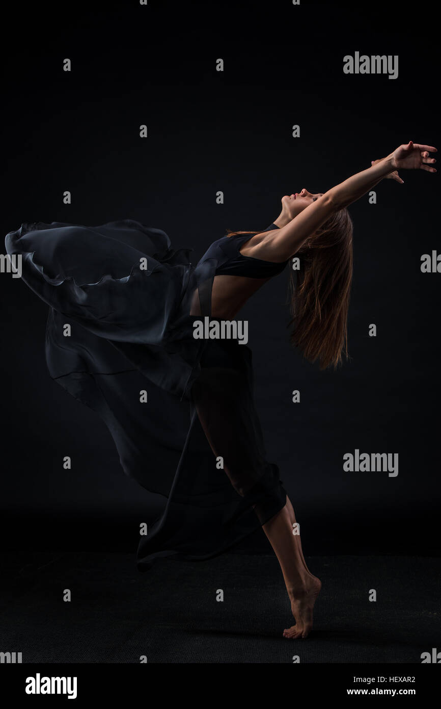 Young beautiful dancer in beige dress dancing on black studio ...