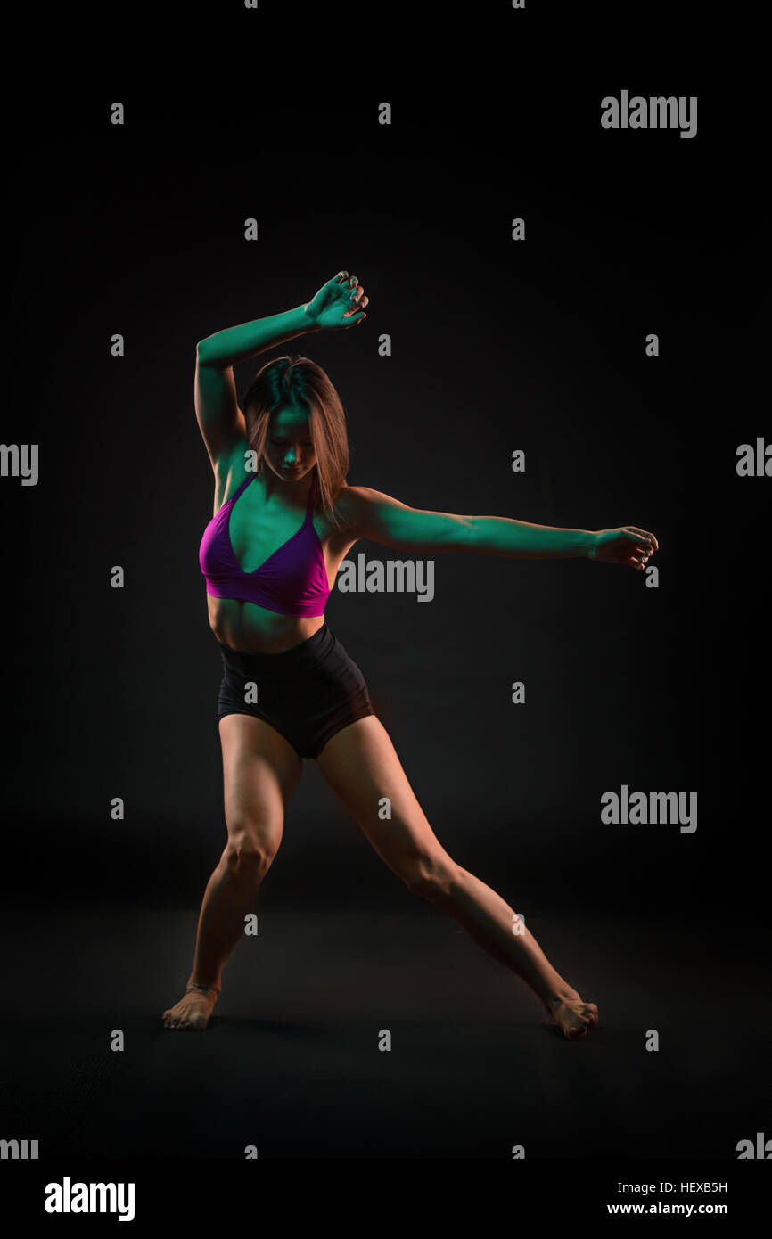 Young beautiful dancer in beige dress dancing on black studio ...