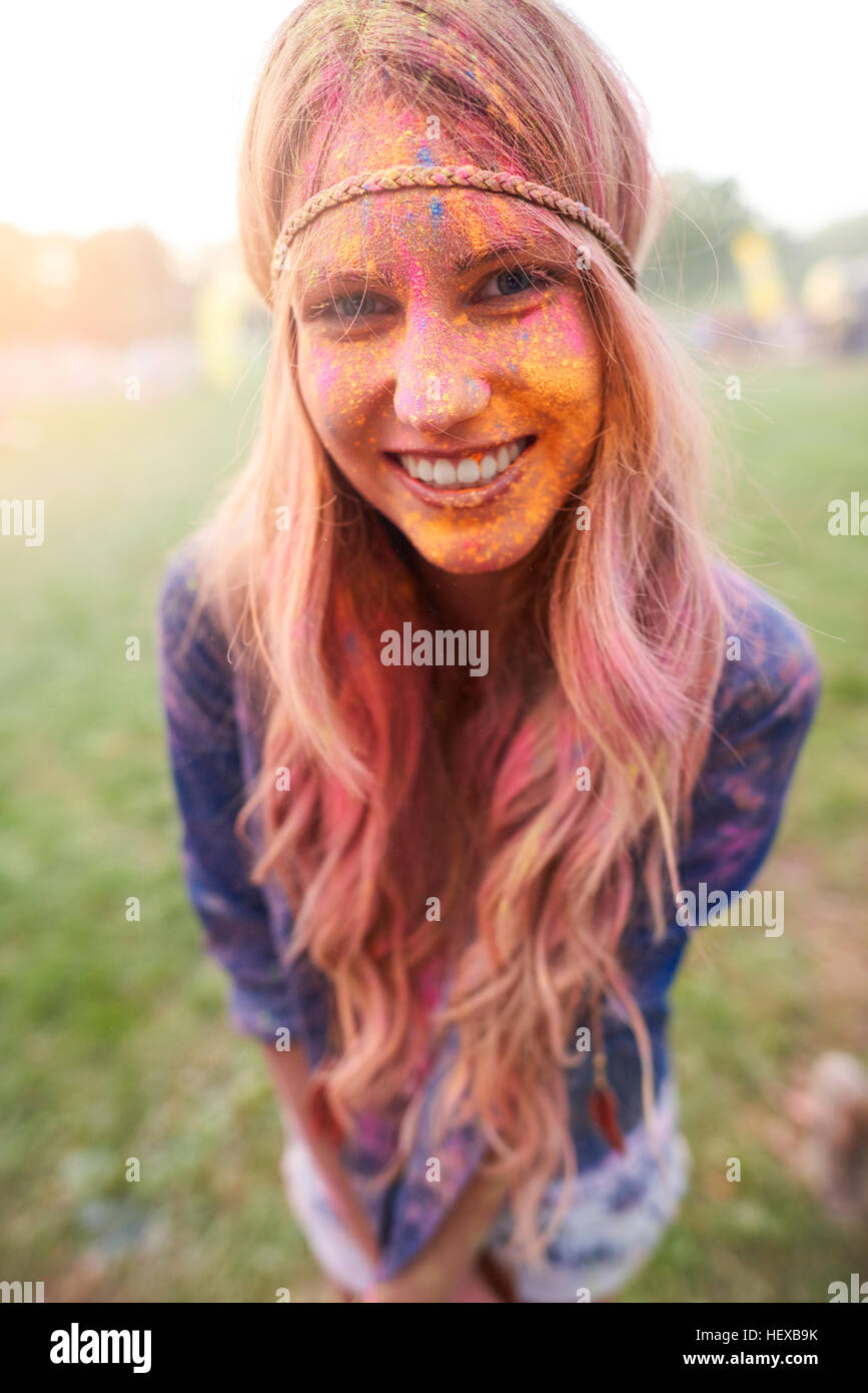 Portrait of young woman at festival, covered in colourful powder paint ...