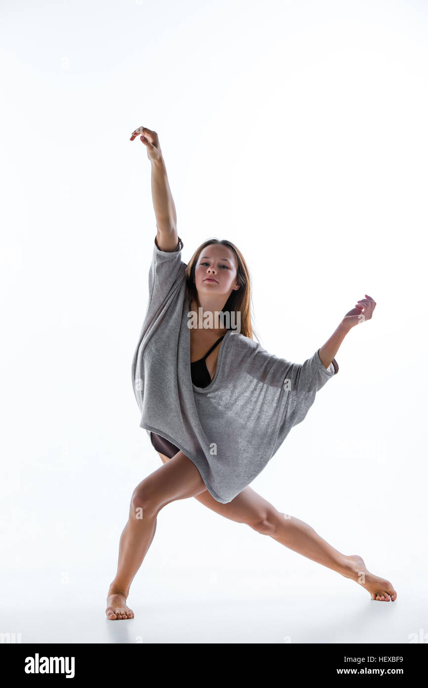 Young beautiful dancer in beige dress dancing on white studio ...