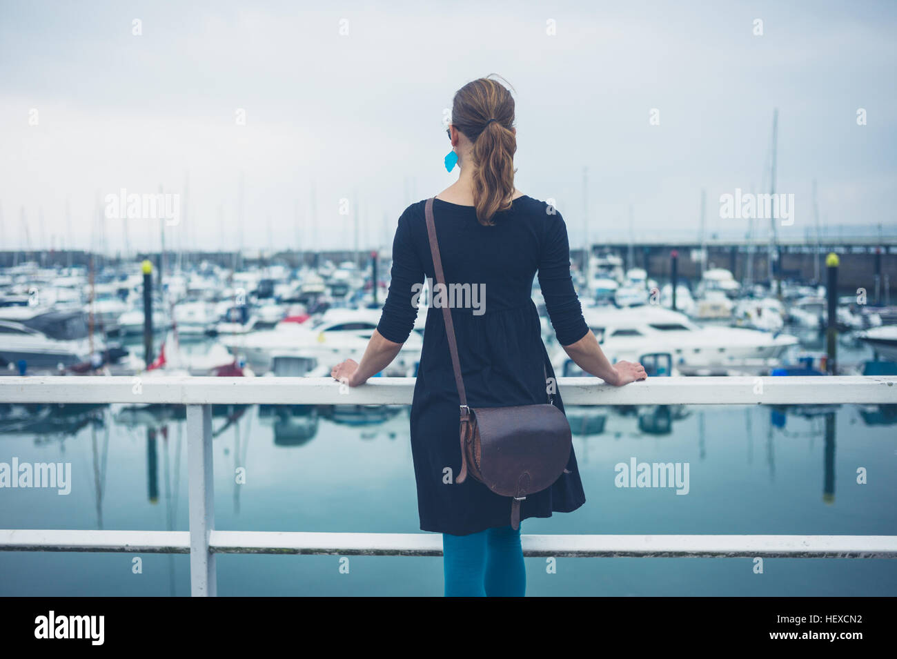 Young woman standing in harbor looking at the boats Stock Photo - Alamy