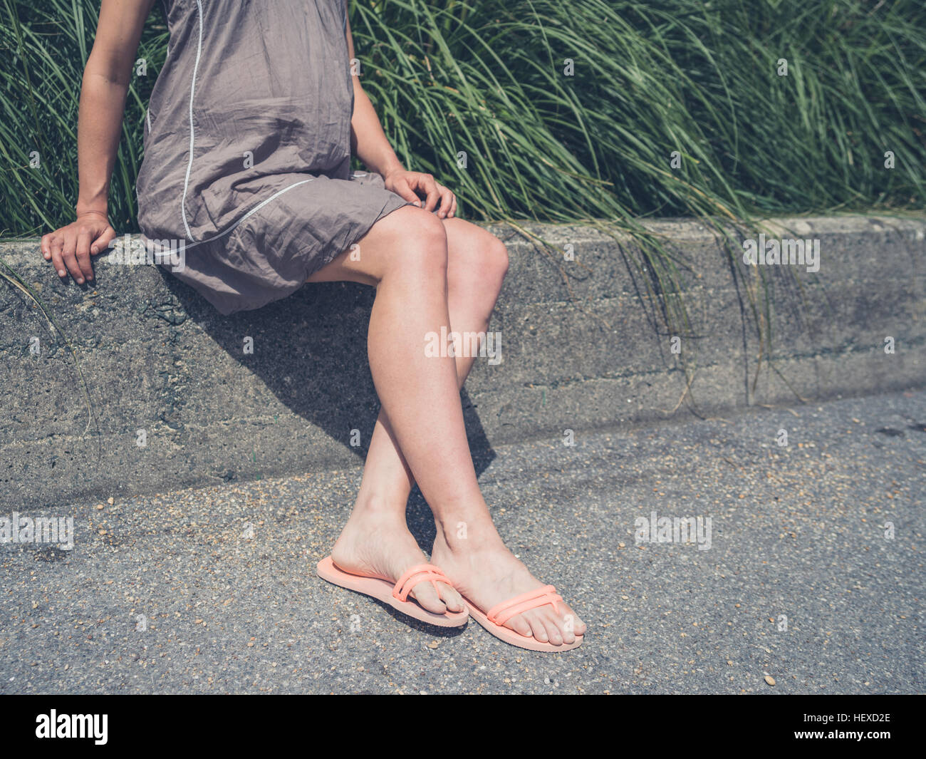 The legs of a young woman as she is sunbathing and sitting outside ...