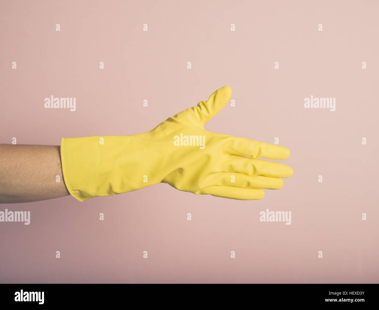 A female hand wearing a yellow rubber glove is offering a handshake ...