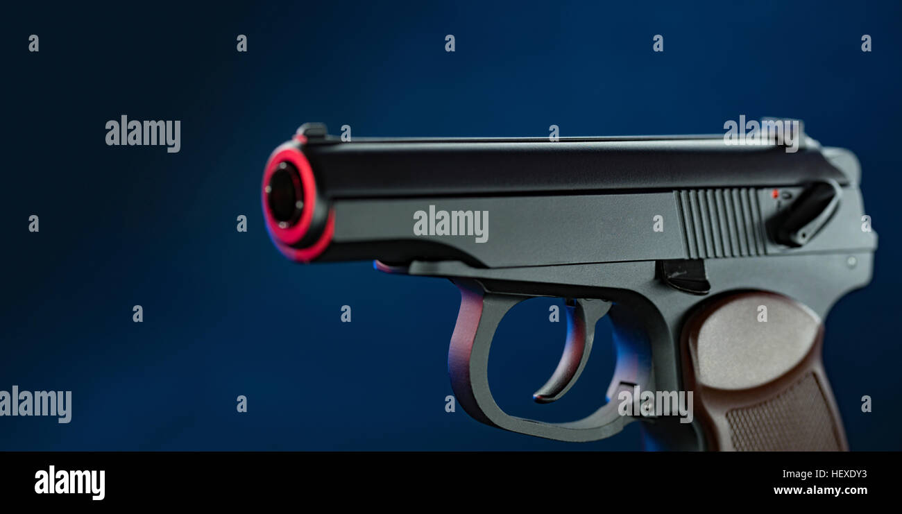 Handgun against a blue background Stock Photo - Alamy