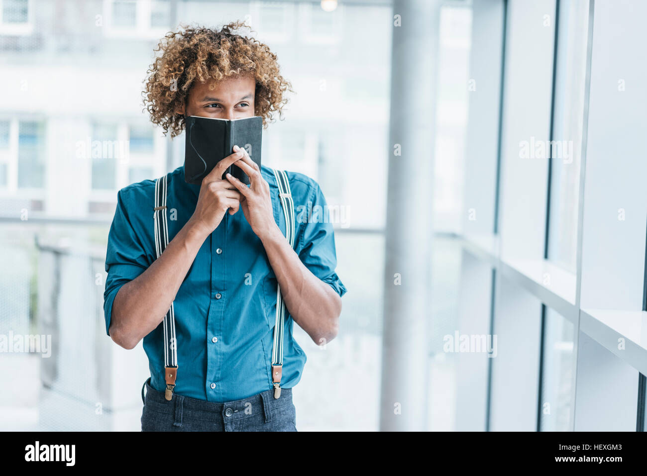 Young man covering face with note book Stock Photo - Alamy