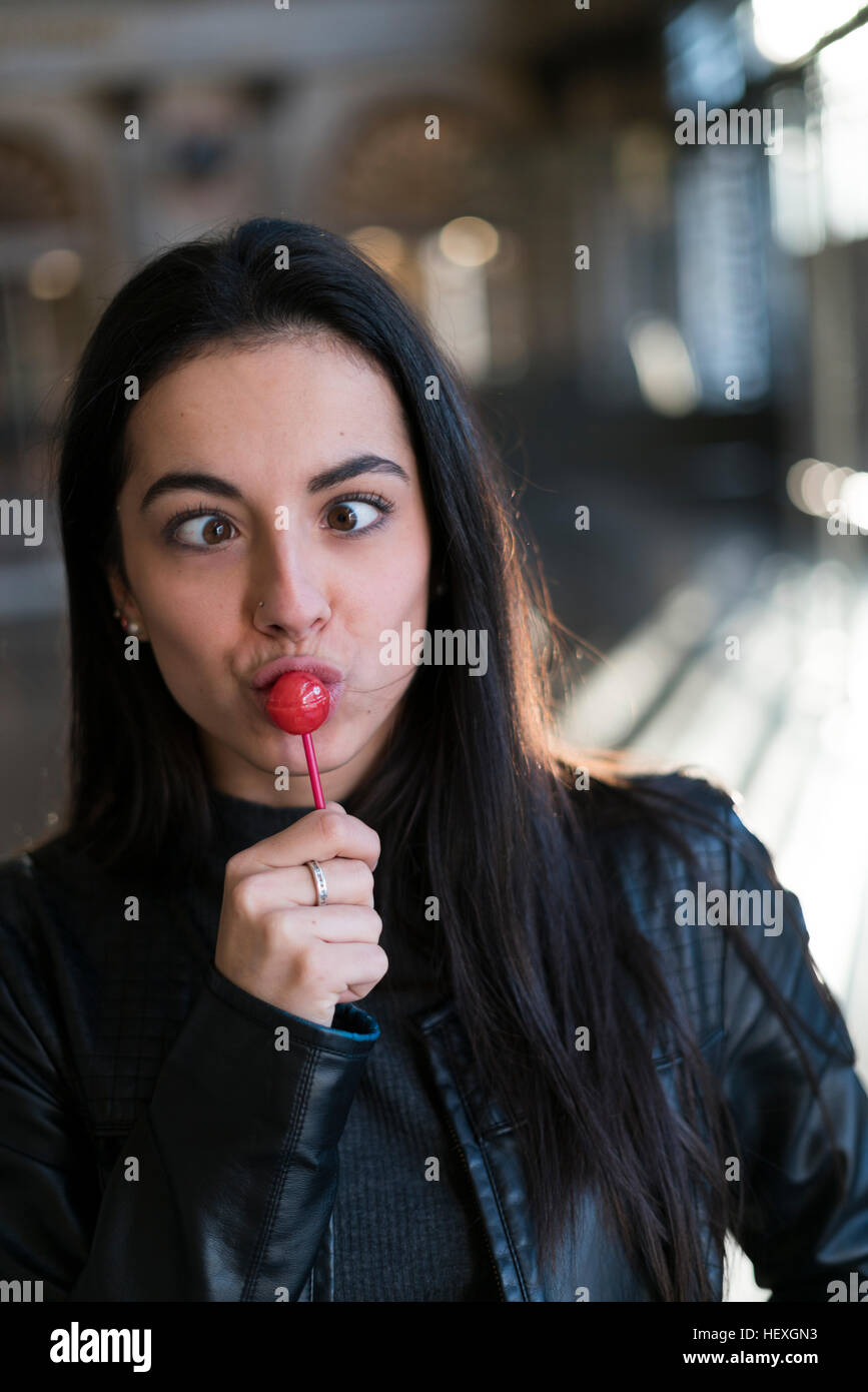 Portrait of young woman with lollipop pulling faces Stock Photo - Alamy