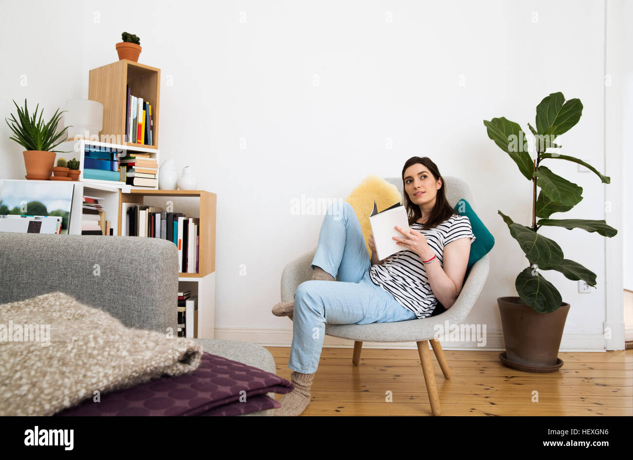 Woman at home sitting on chair looking up Stock Photo - Alamy