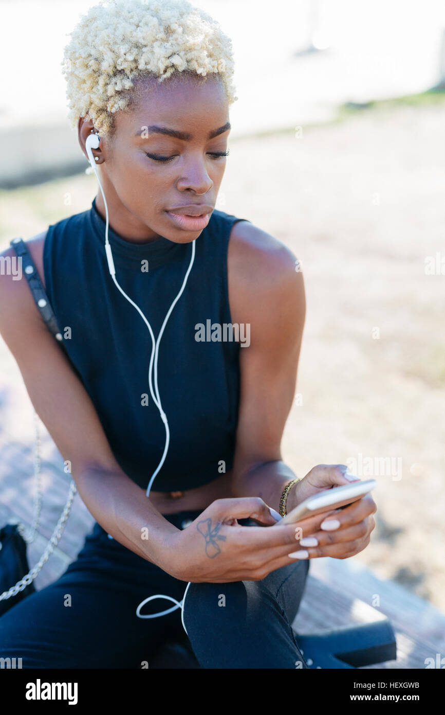 Young woman with cell phone and earbuds Stock Photo - Alamy