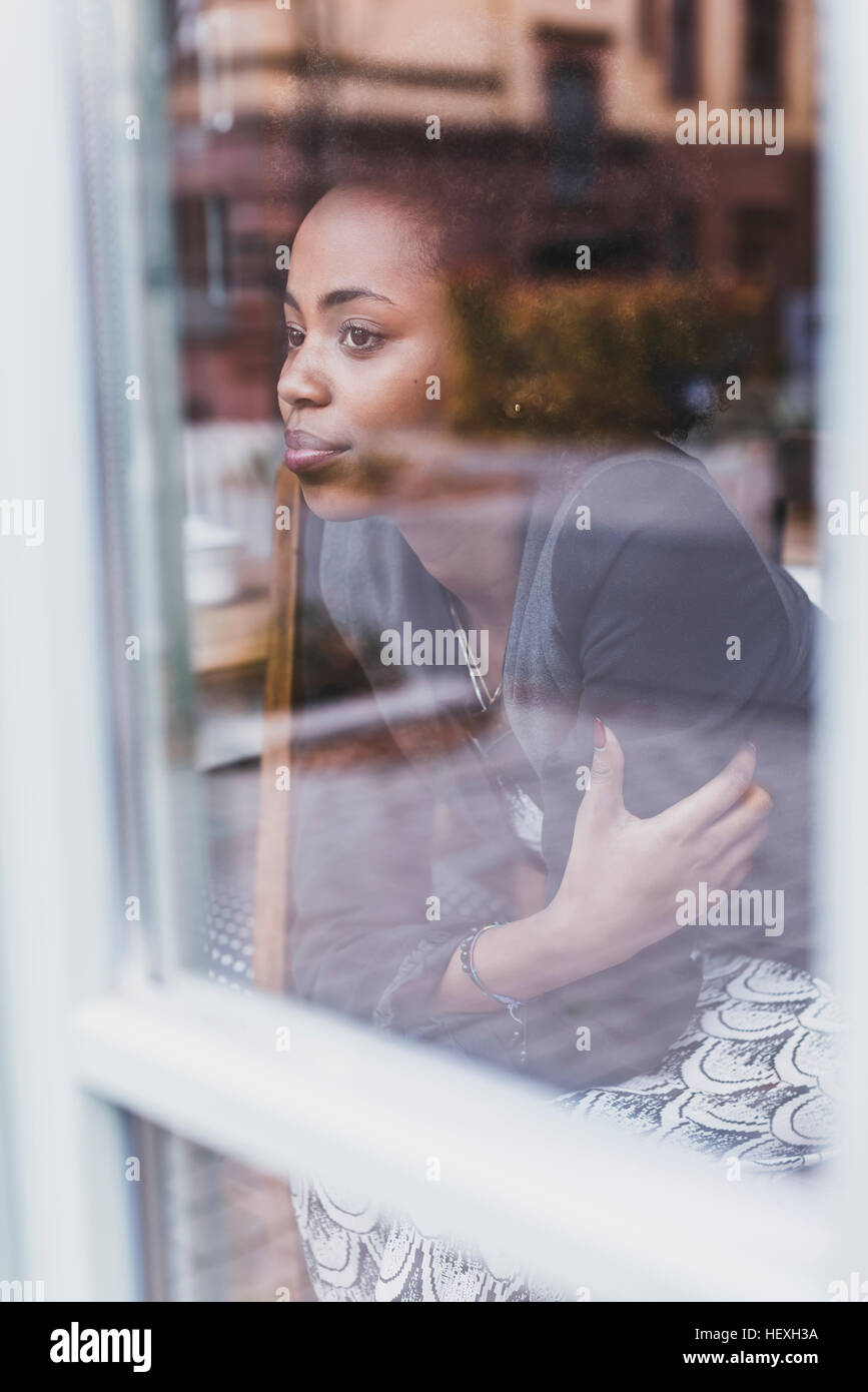 Young woman in a cafe looking out of window Stock Photo - Alamy