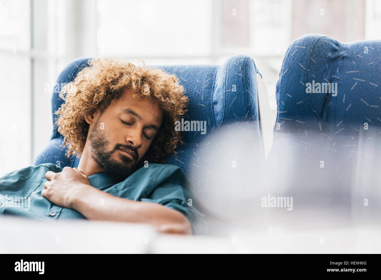 Young man sleeping in arm chair Stock Photo - Alamy
