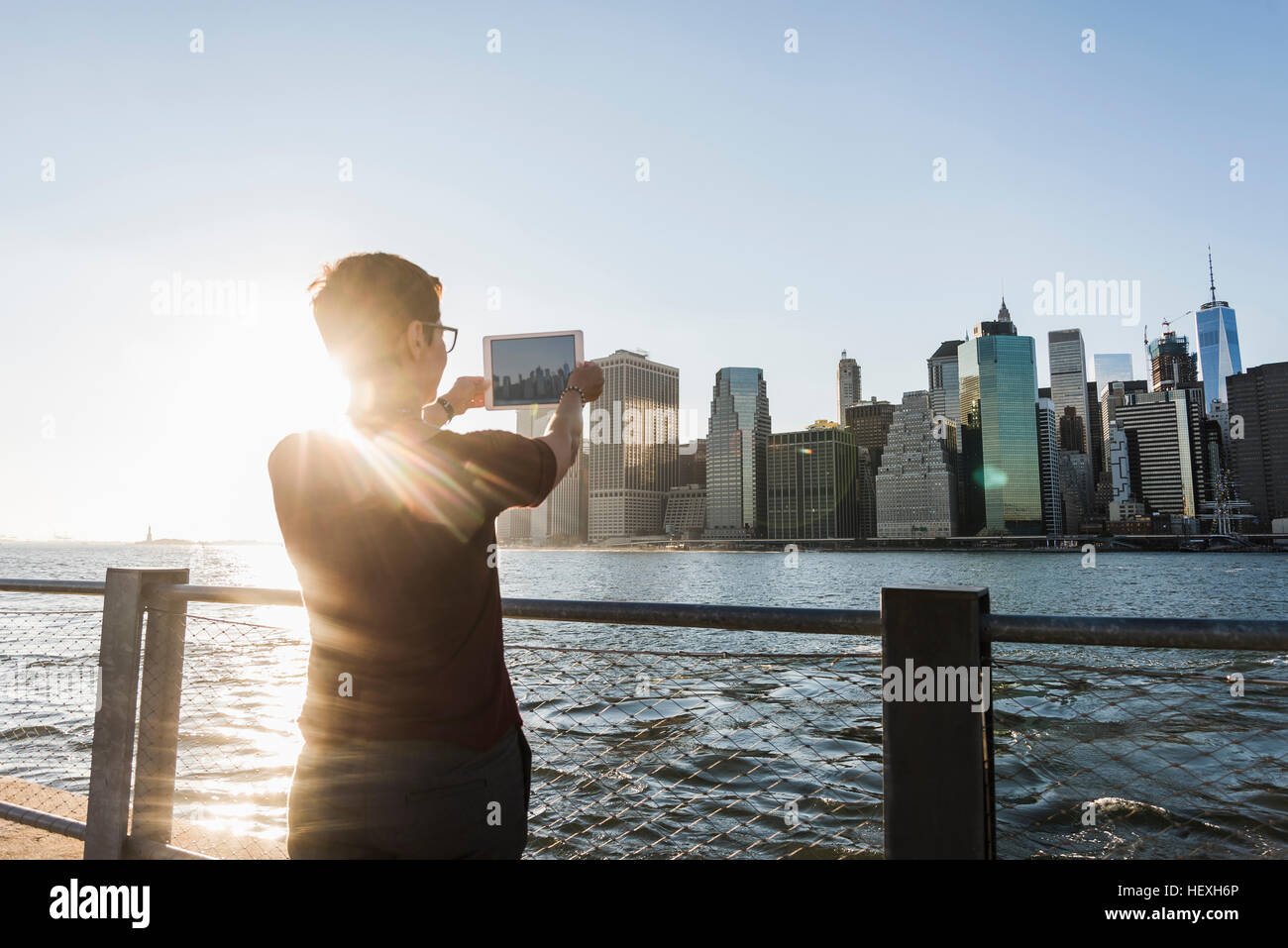USA, Brooklyn, back view of woman taking picture of Manhattan skyline ...