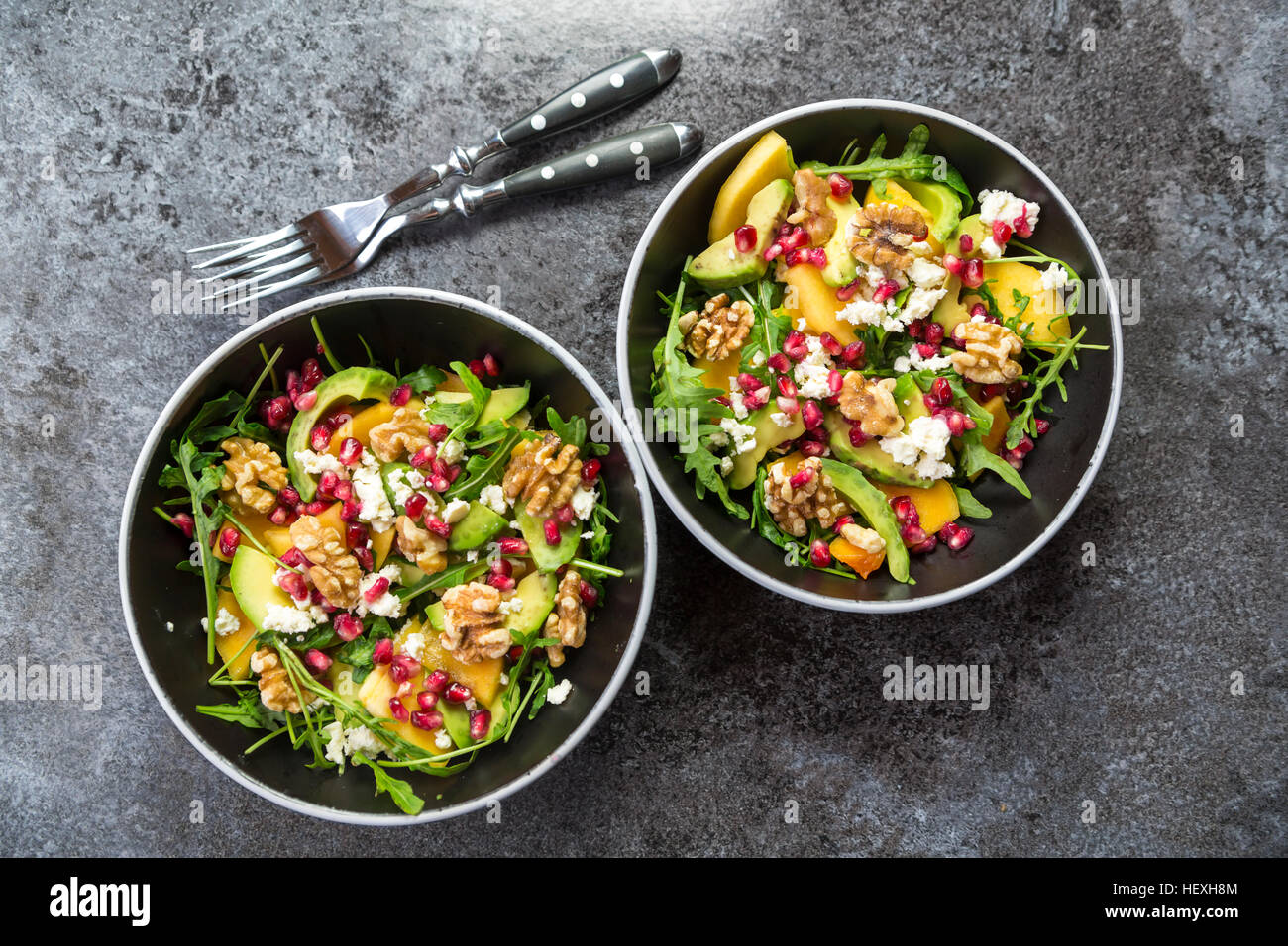 Two bowls of avocado salad with rocket, pomegranate seed, kaki, feta ...