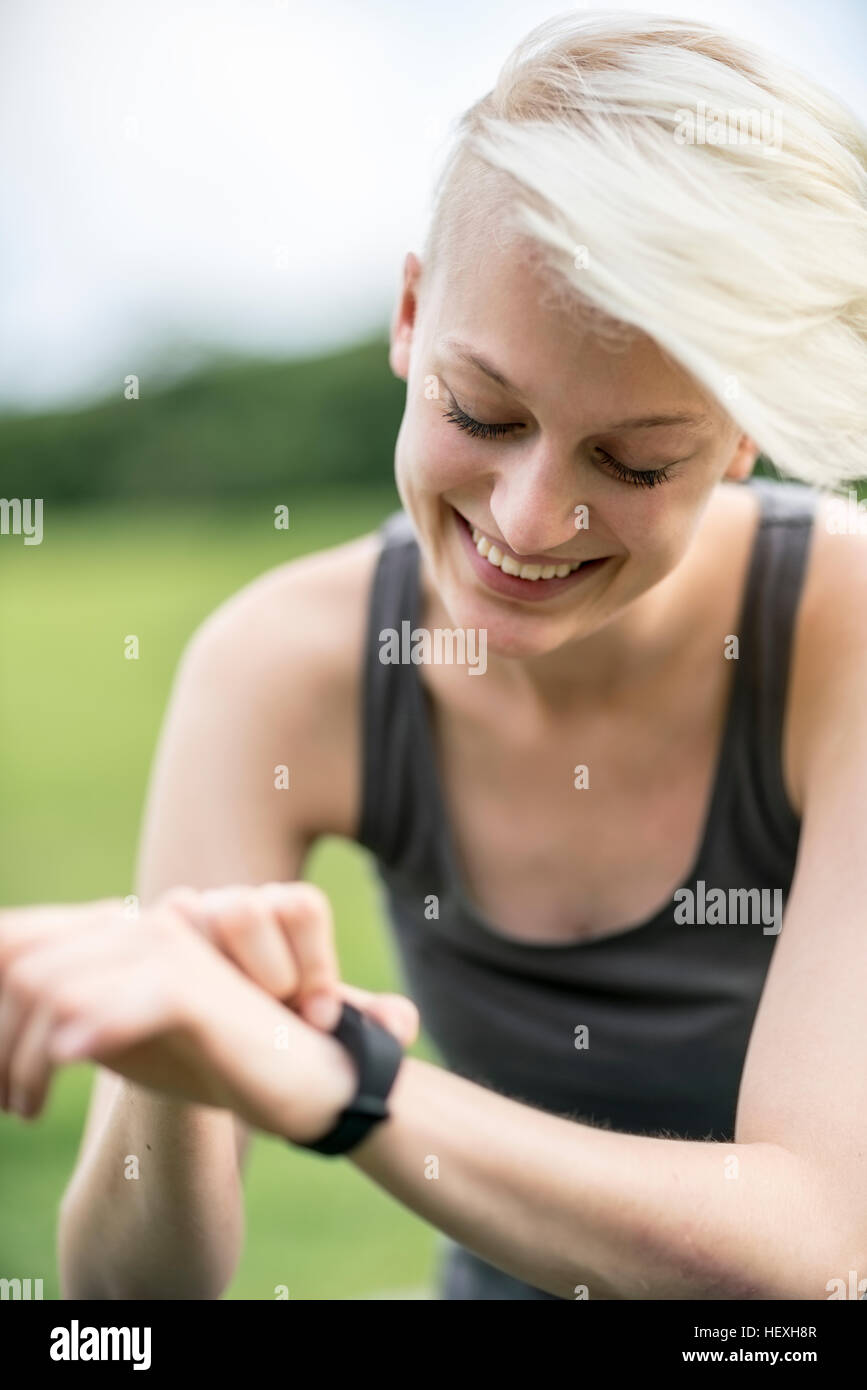 Smiling young woman checking her smartwatch Stock Photo - Alamy