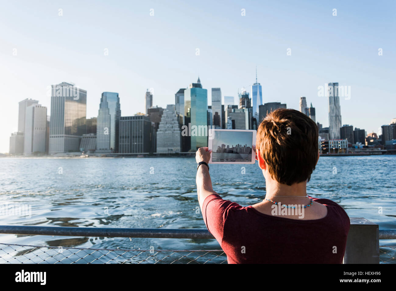 USA, Brooklyn, back view of woman taking picture of Manhattan skyline ...