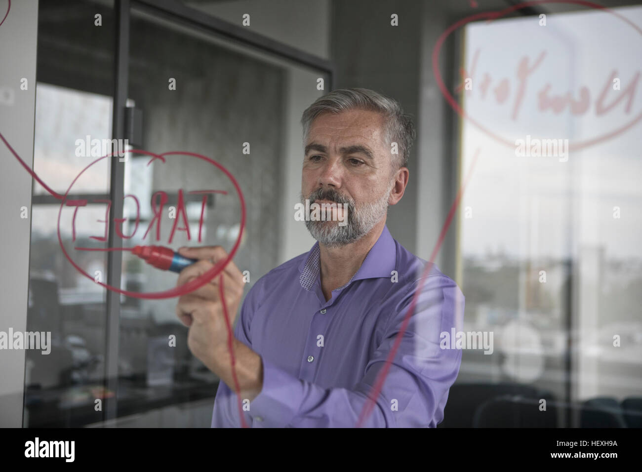 Businessman in office writing on glass wall Stock Photo - Alamy