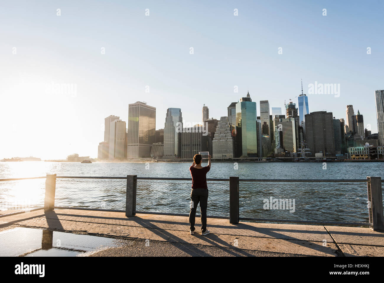 USA, Brooklyn, back view of woman taking picture of Manhattan skyline ...