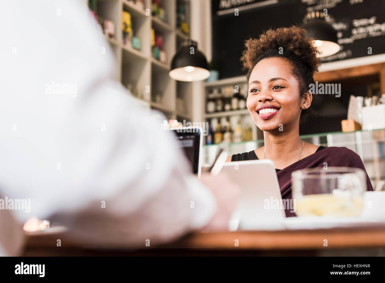 Waitress at counter in a cafe smiling at customer Stock Photo - Alamy