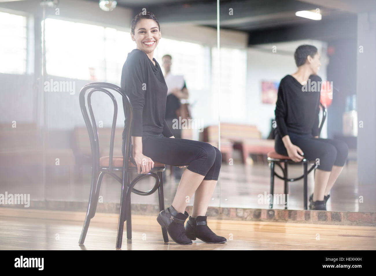 Portrait of smiling female dancer sitting on chair in dance studio ...