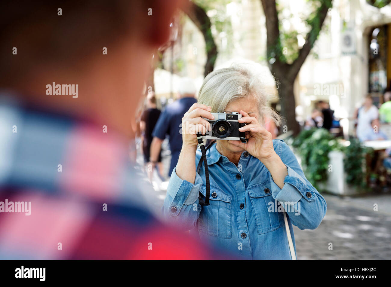 Senior woman taking picture of her partner with camera Stock Photo - Alamy