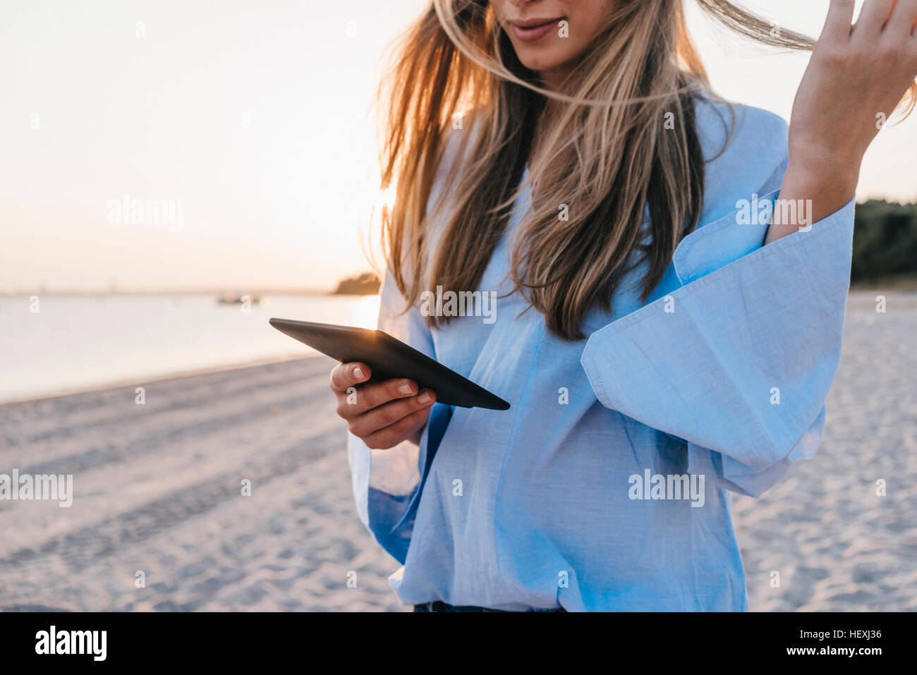 Young woman using tablet on the beach, partial view Stock Photo - Alamy