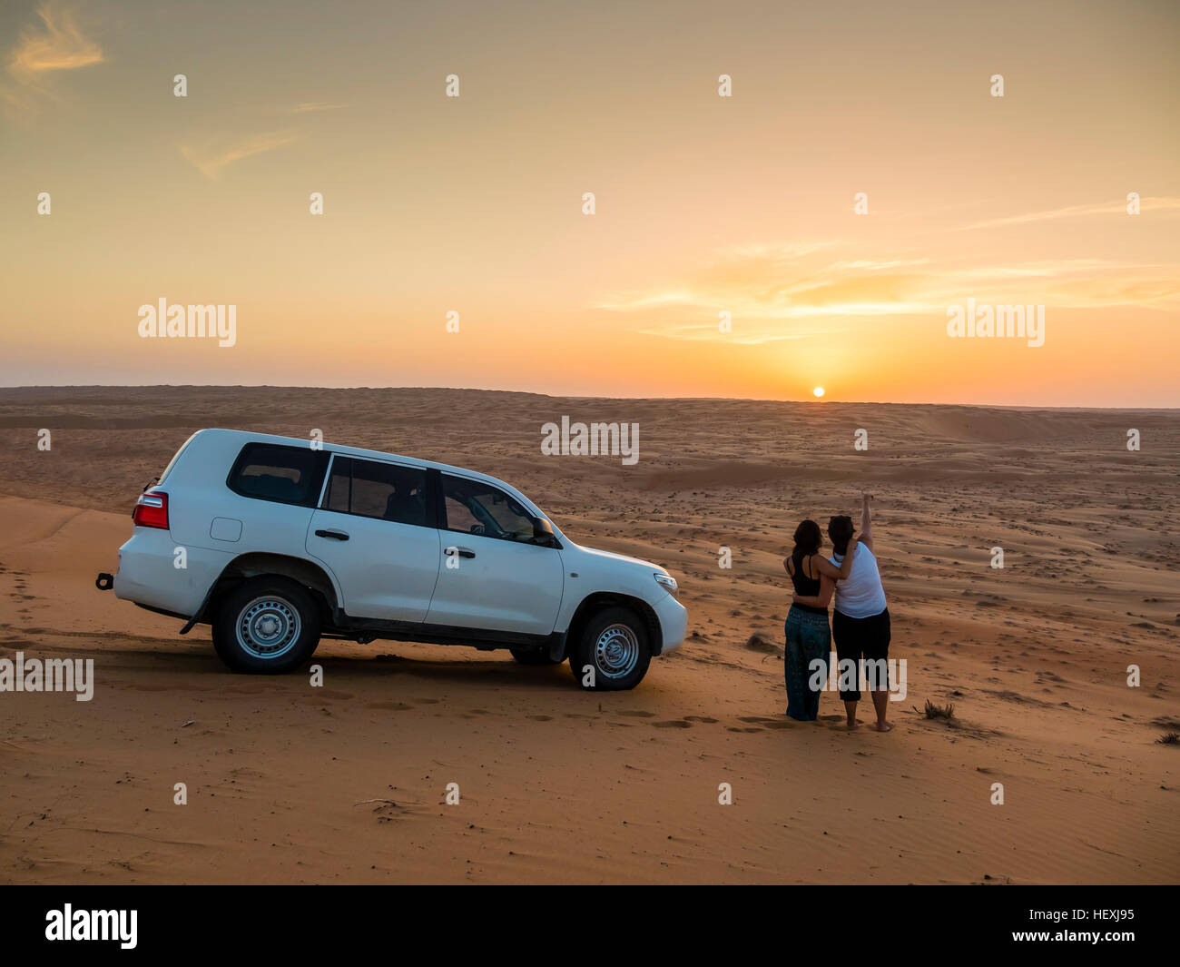 Oman, Al Raka, two young women standing besides off-road vehicle on a ...