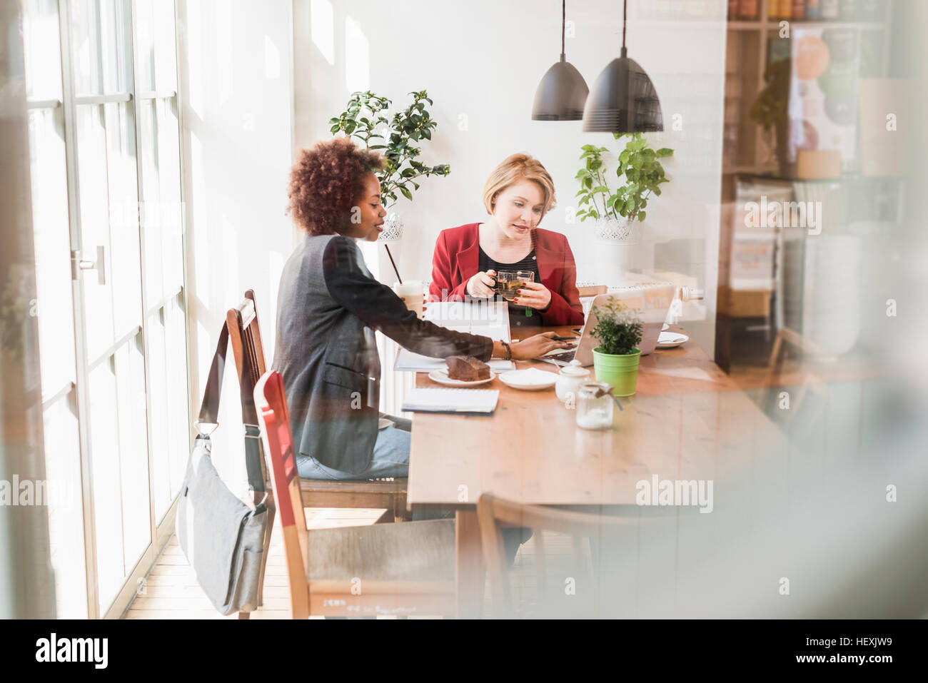 Two young women using laptop in a cafe Stock Photo - Alamy