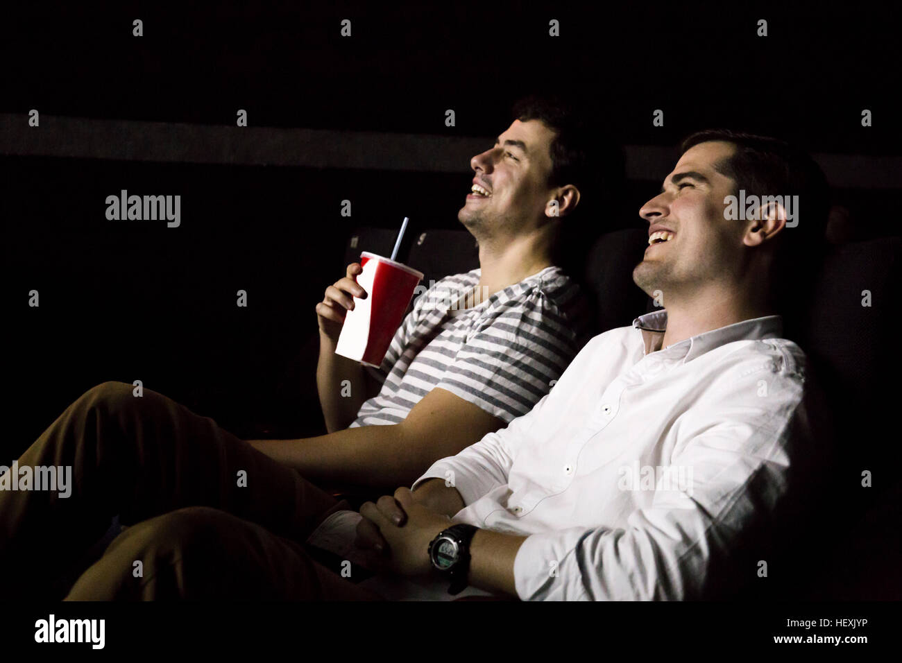 Two men watching a movie in a cinema Stock Photo - Alamy