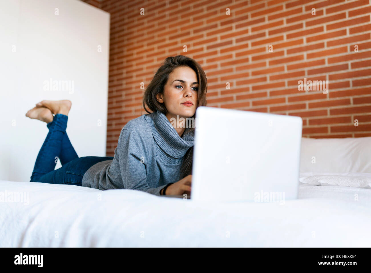 Young woman lying on bed using laptop Stock Photo - Alamy