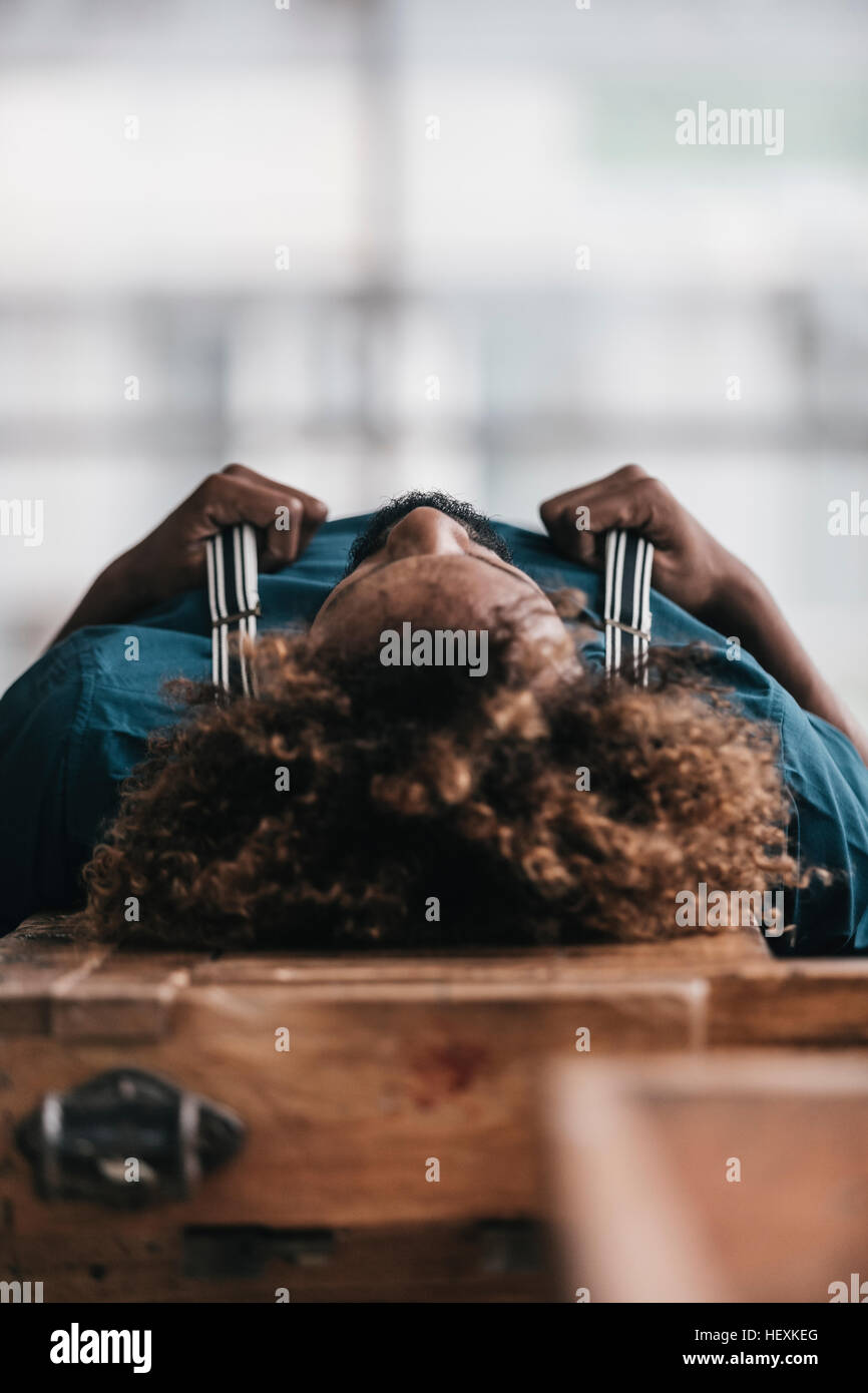 Young man lying on work bench, overhead view Stock Photo - Alamy