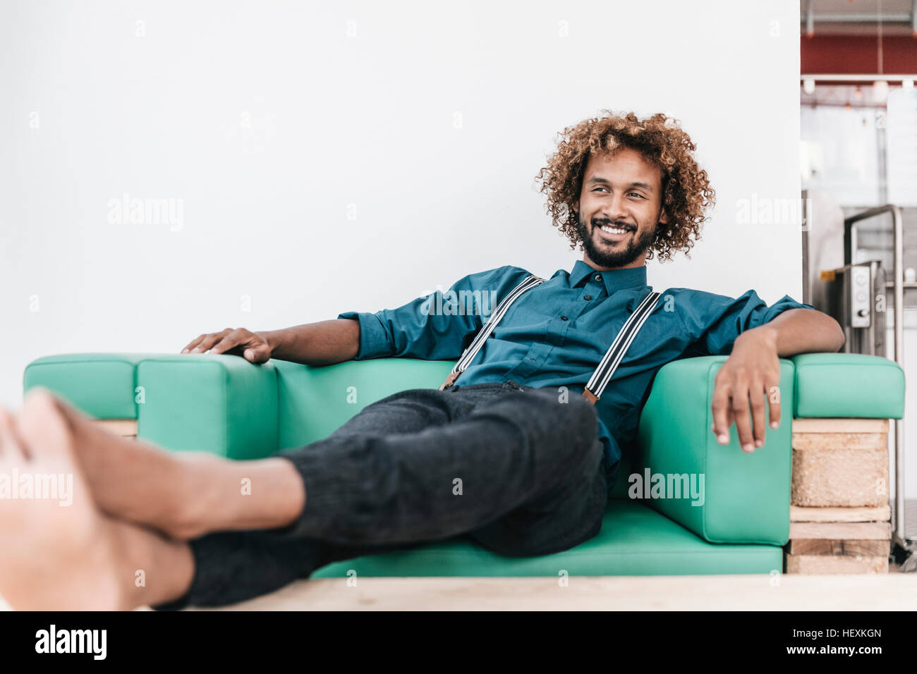 Young man relaxed in arm chair with feet up Stock Photo - Alamy