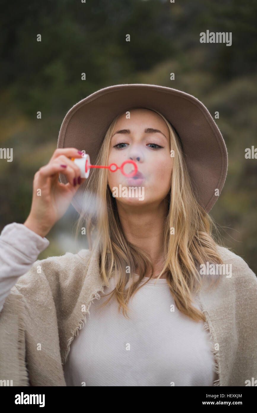 Young woman wearing hat blowing soap bubbles Stock Photo - Alamy