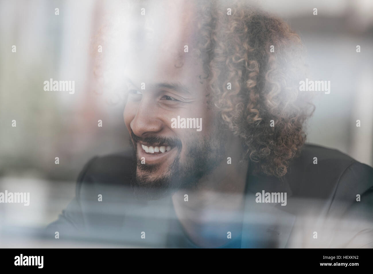 Young man smiling behind glass pane Stock Photo - Alamy