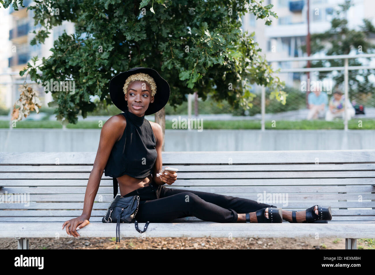 Young woman sitting on bench Stock Photo - Alamy