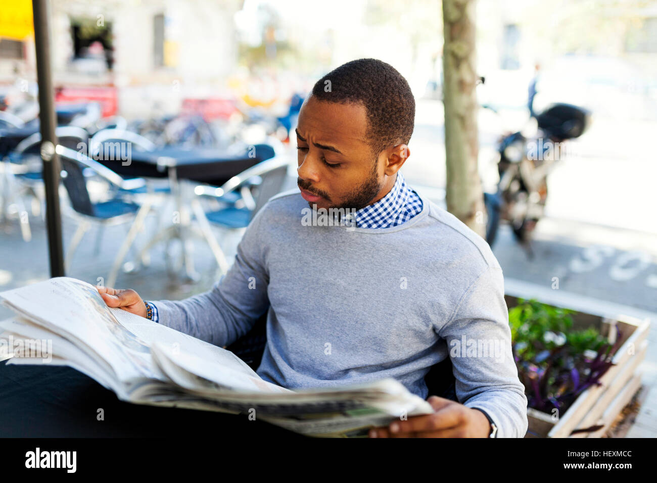 Young man reading newspaper at street cafe Stock Photo - Alamy