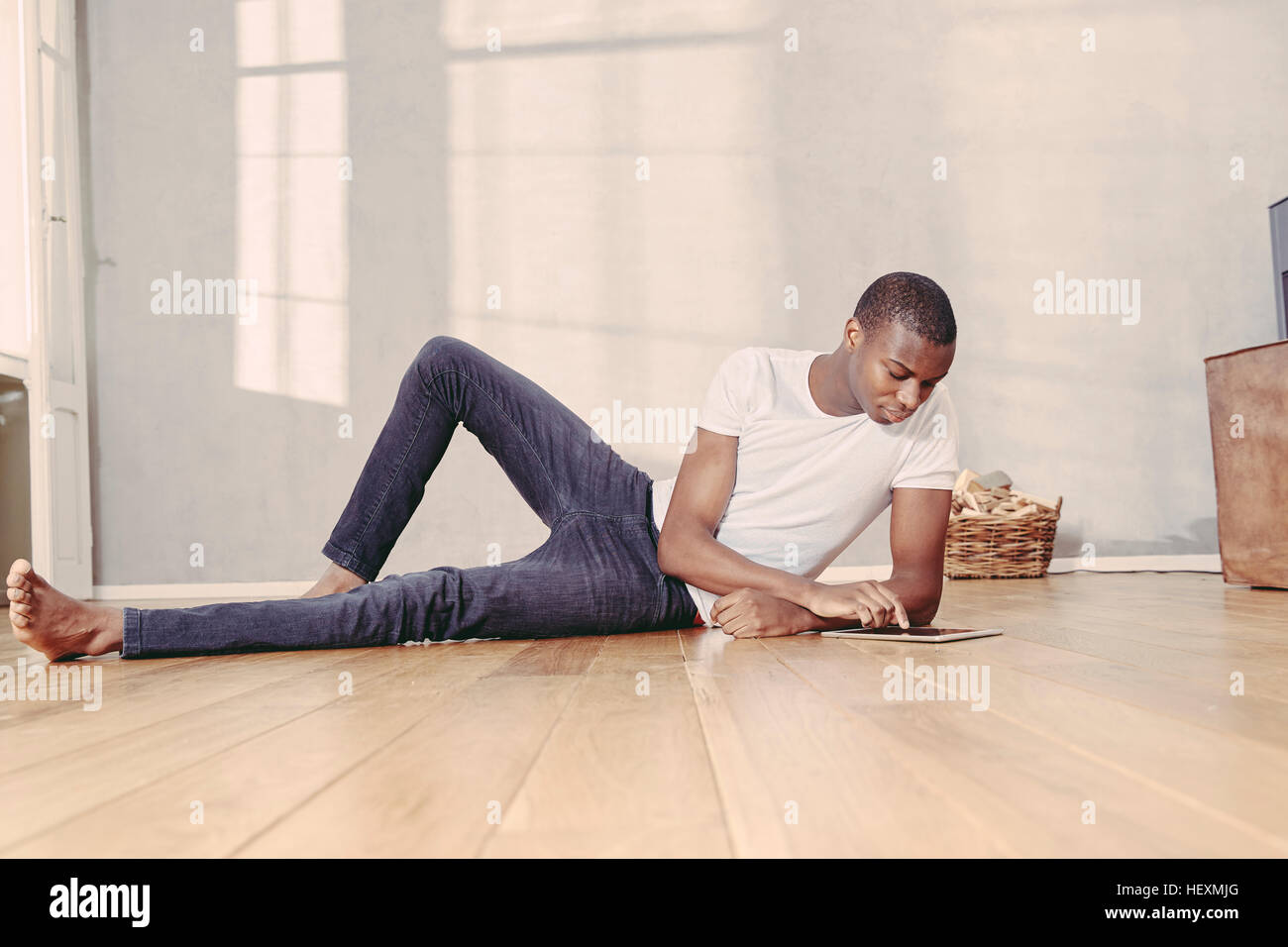 Young man lying on floor using tablet Stock Photo - Alamy
