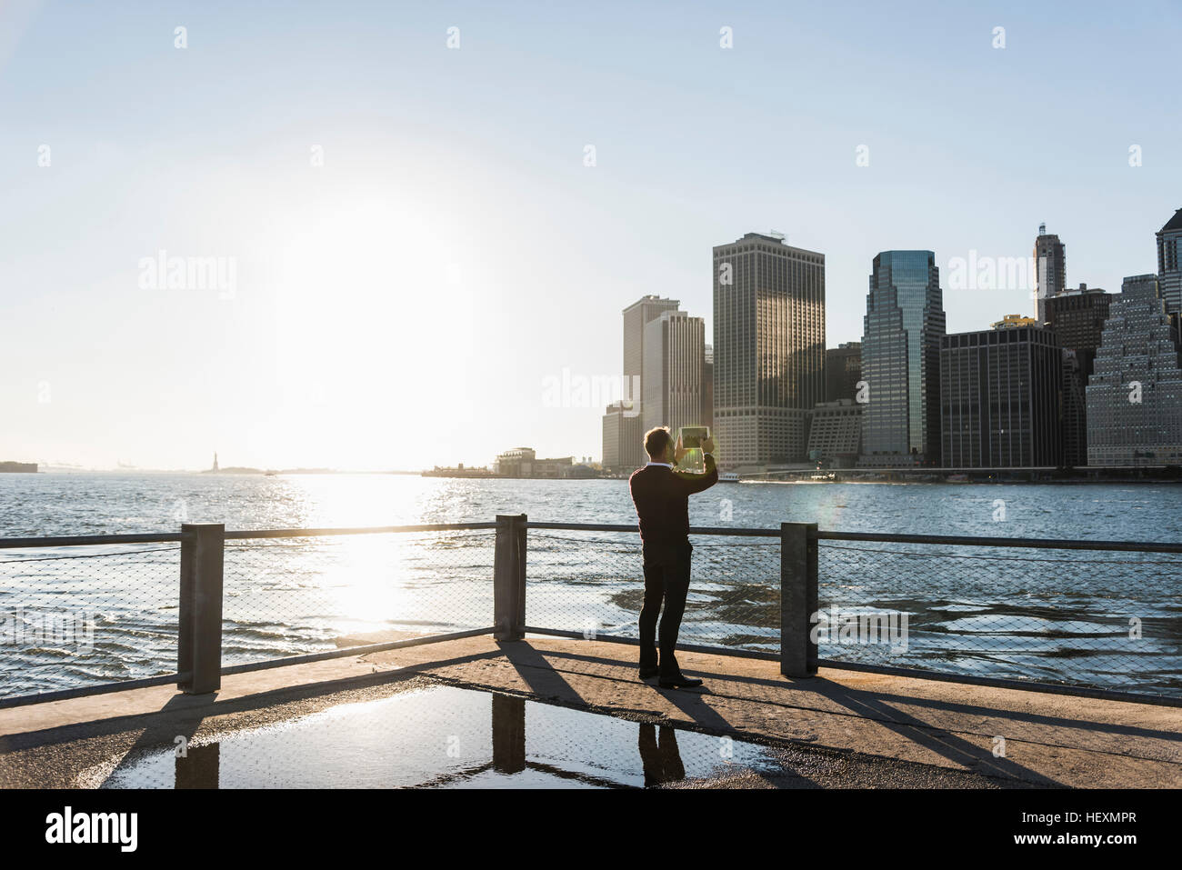USA, Brooklyn, back view of man taking picture of Manhattan skyline ...