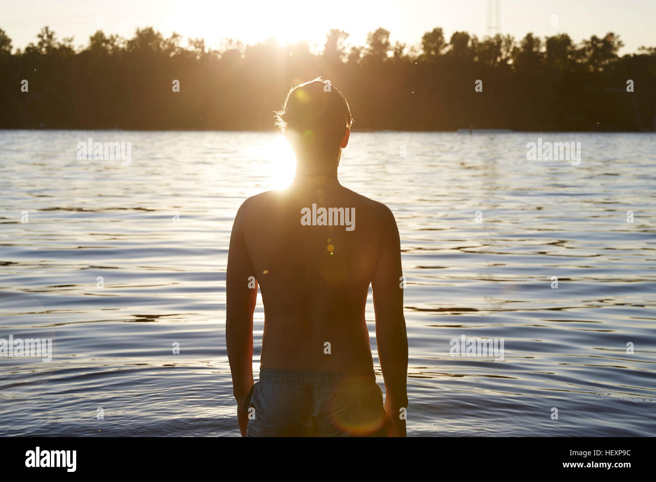 Back view of man in a lake at sunset Stock Photo - Alamy