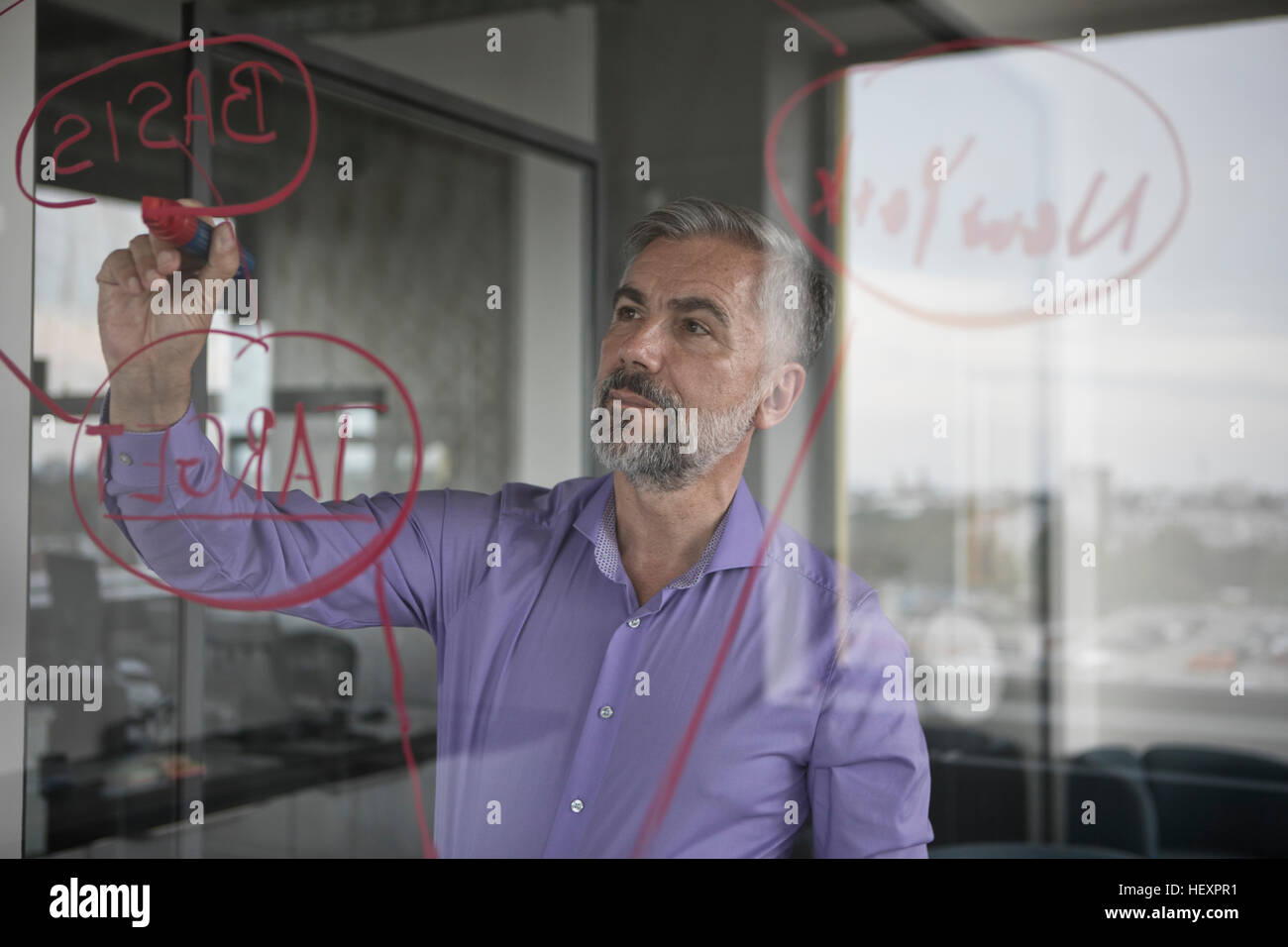 Businessman in office writing on glass wall Stock Photo - Alamy