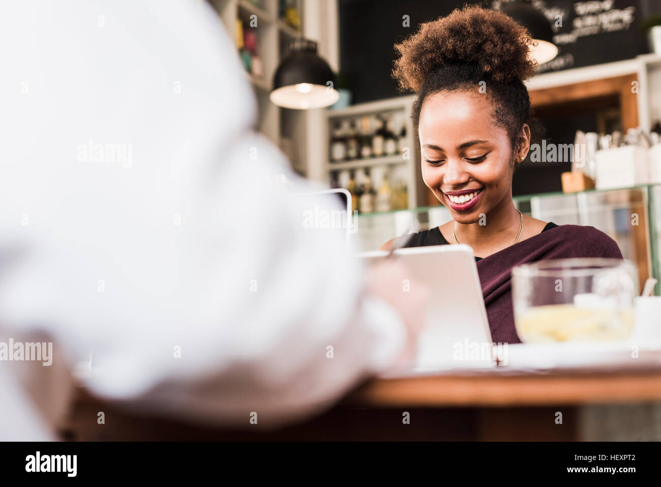 Smiling waitress at counter in a cafe with customer Stock Photo - Alamy