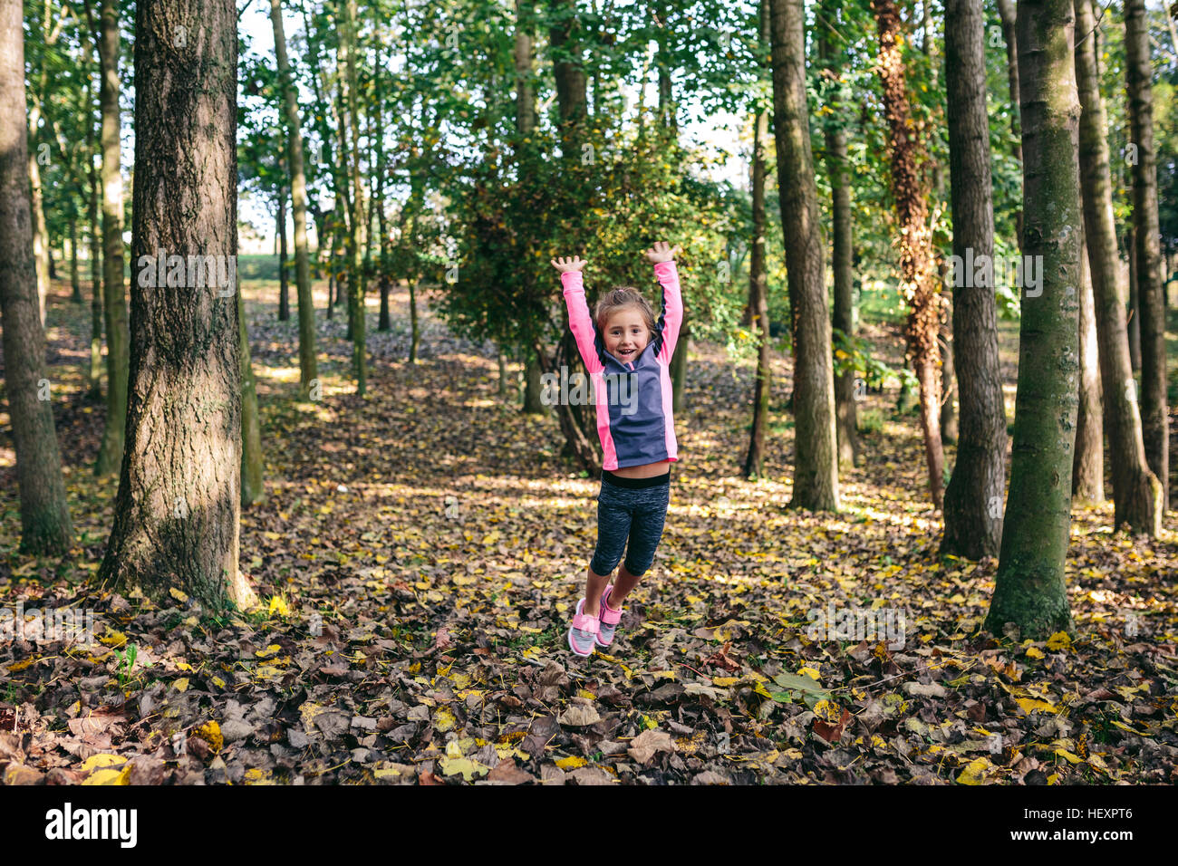 Happy little girl jumping in the air in the woods Stock Photo - Alamy