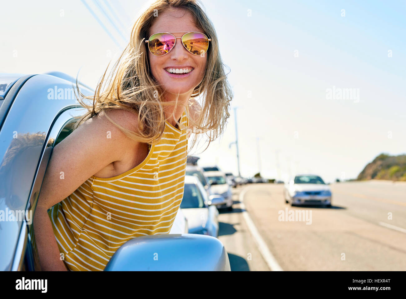 Happy young woman leaning out of car window Stock Photo - Alamy