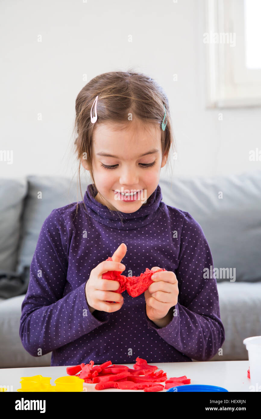 Little girl kneading red modeling clay Stock Photo - Alamy