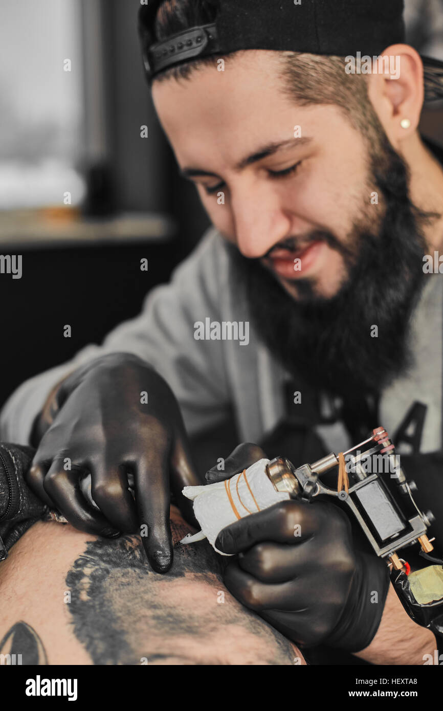 Tattoo master is tattooing in the tattoosalon Stock Photo - Alamy