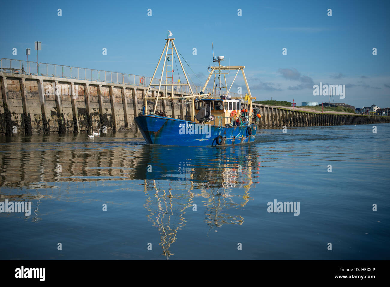 A fishing trawler boat leaves Littlehampton Harbour on a calm morning ...
