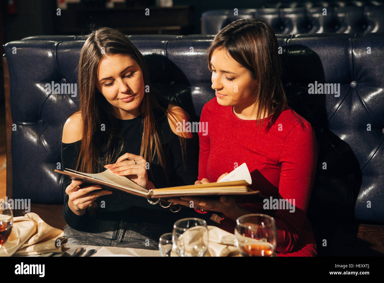 two beautiful women look at the menu in the restaurant Stock Photo - Alamy